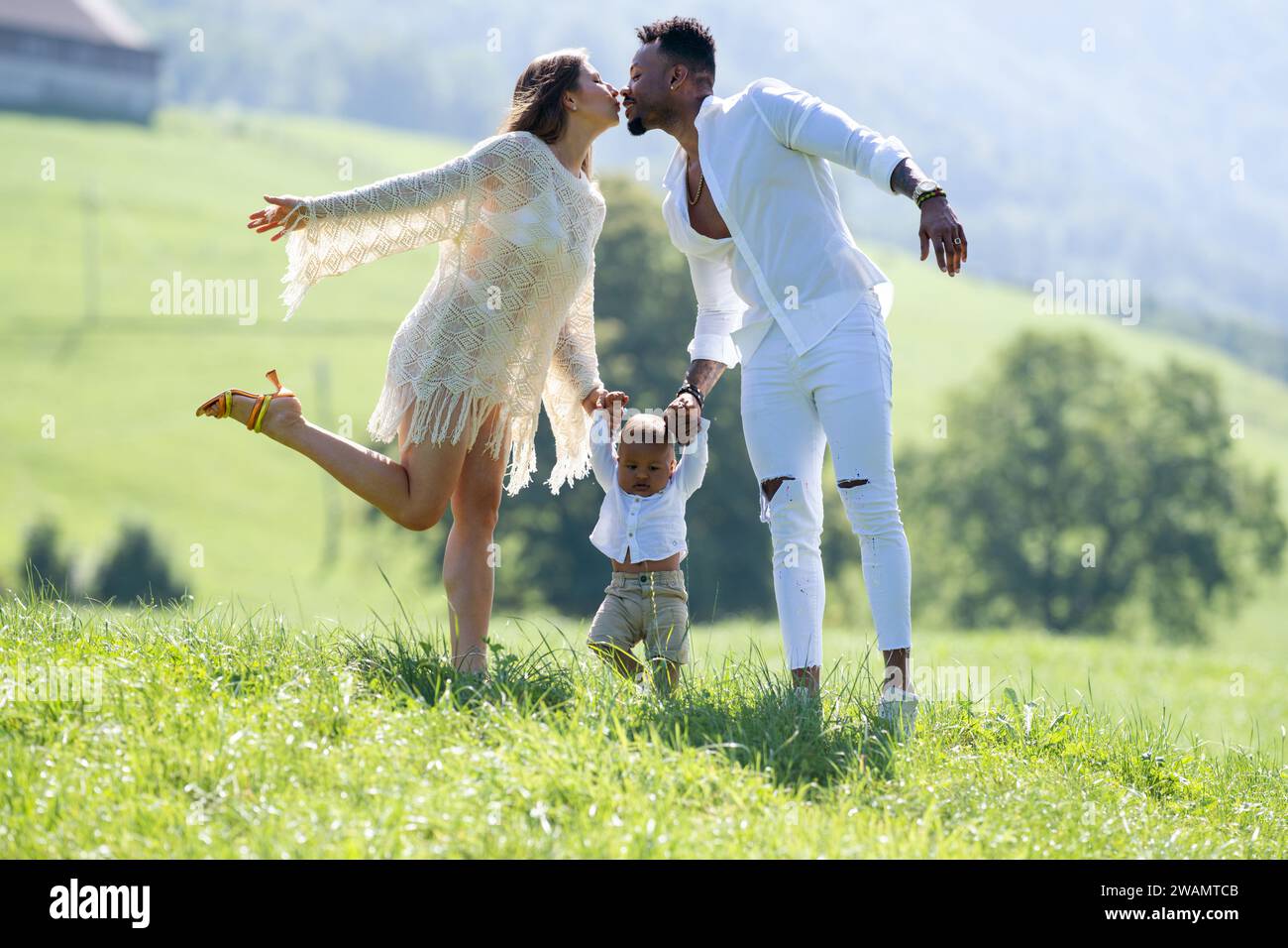 Multiethnic parents and mixed race baby walking on summer grass ...