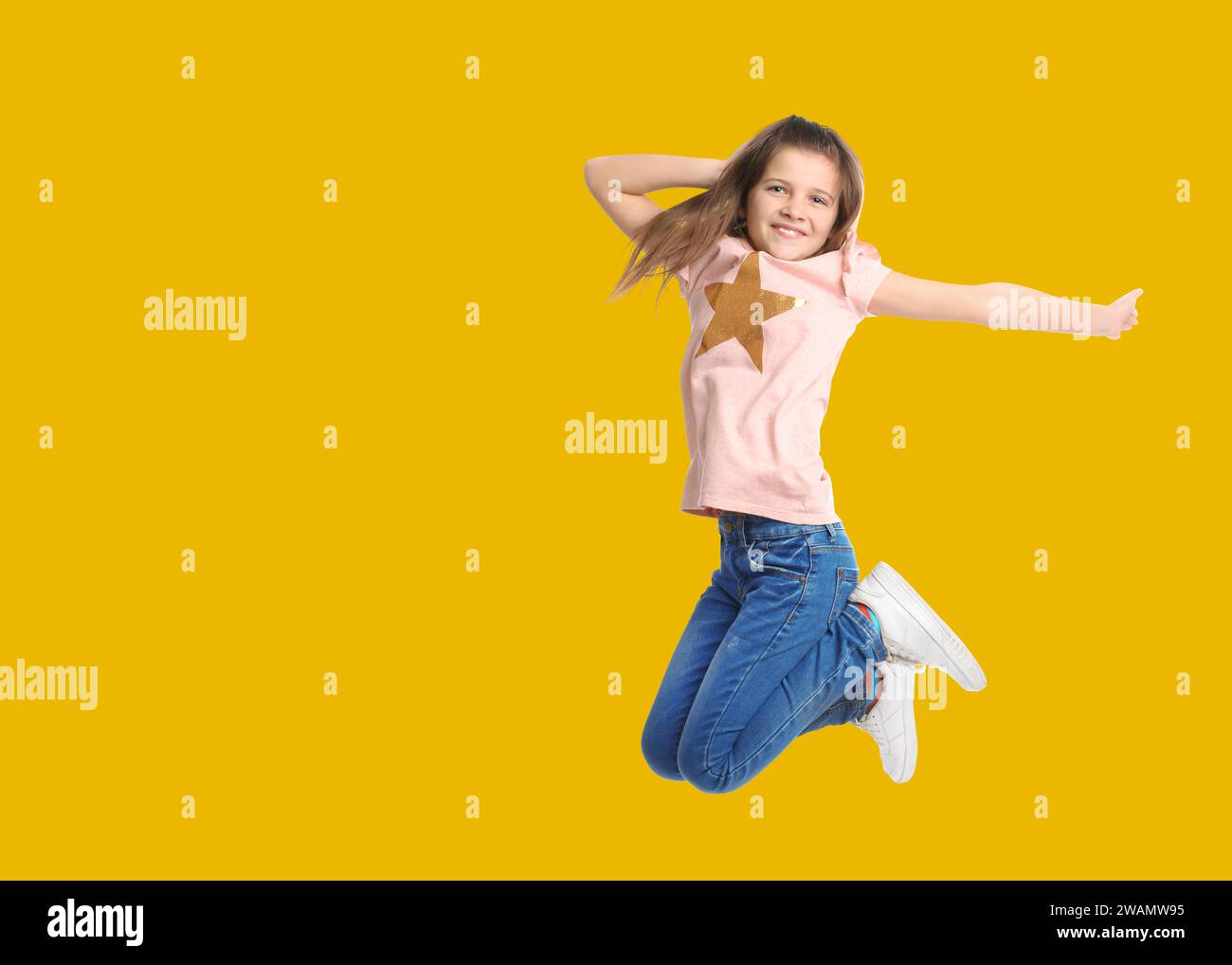 Cute girl jumping on golden background, space for text Stock Photo - Alamy