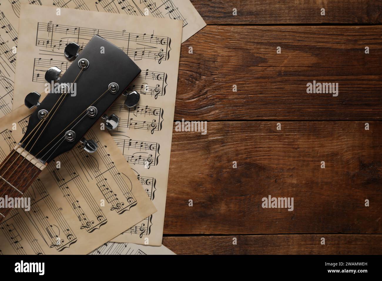 Paper sheets with music notes and acoustic guitar on wooden table, top ...