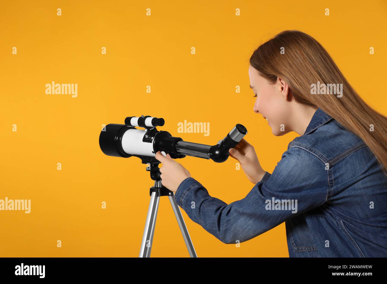 Young astronomer looking at stars through telescope on orange ...