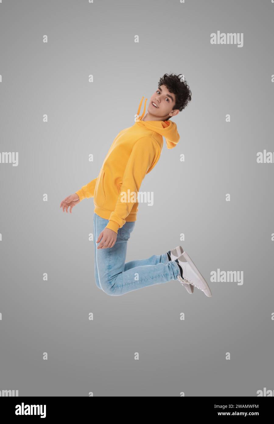Teenage boy jumping on grey background, full length portrait Stock ...
