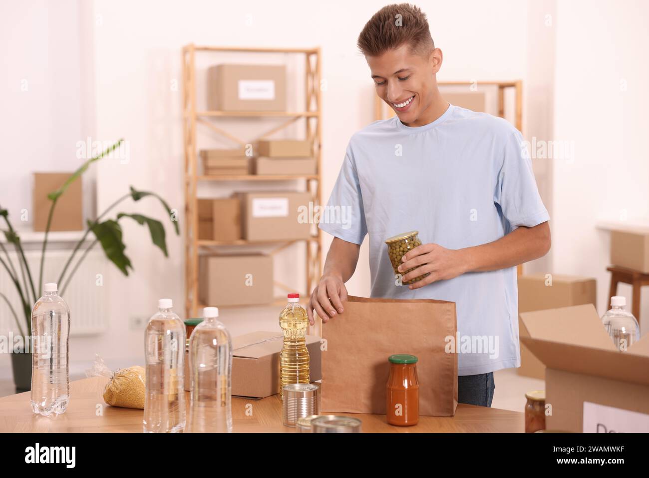Volunteer packing food products at table in warehouse Stock Photo - Alamy