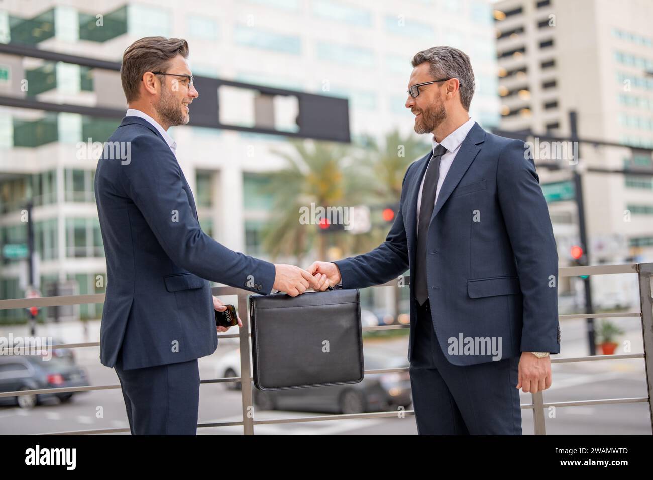 Men in suits handover briefcase outdoor. Business deal. Two business ...