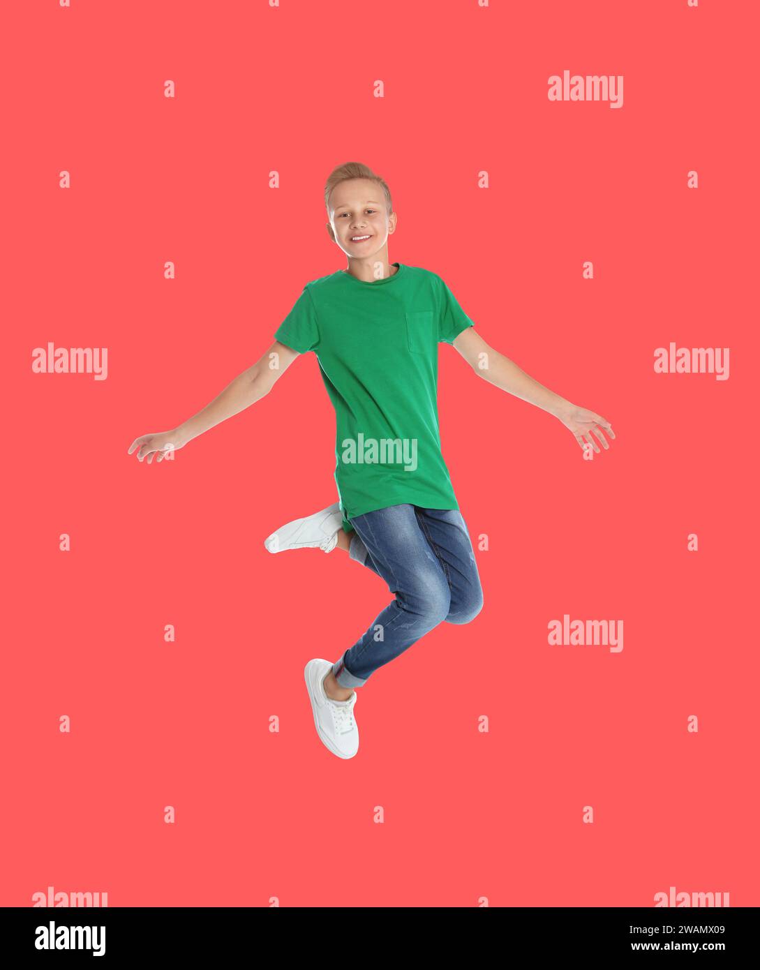 Teenage boy jumping on red background, full length portrait Stock Photo ...