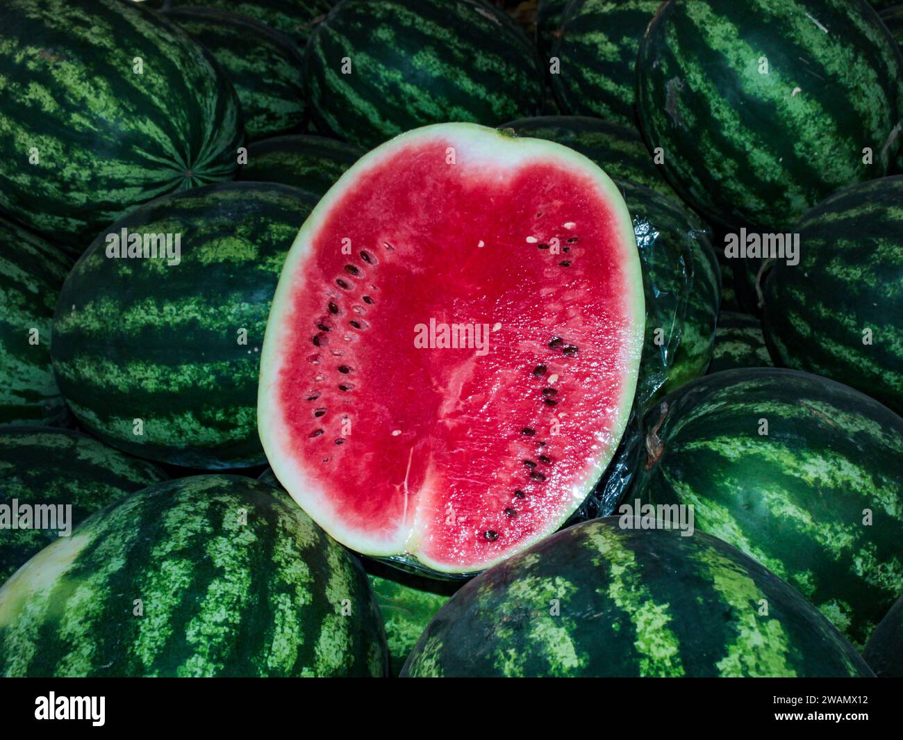 Half of a watermelon, the Citrullus lanatus, with a portion of fresh ...