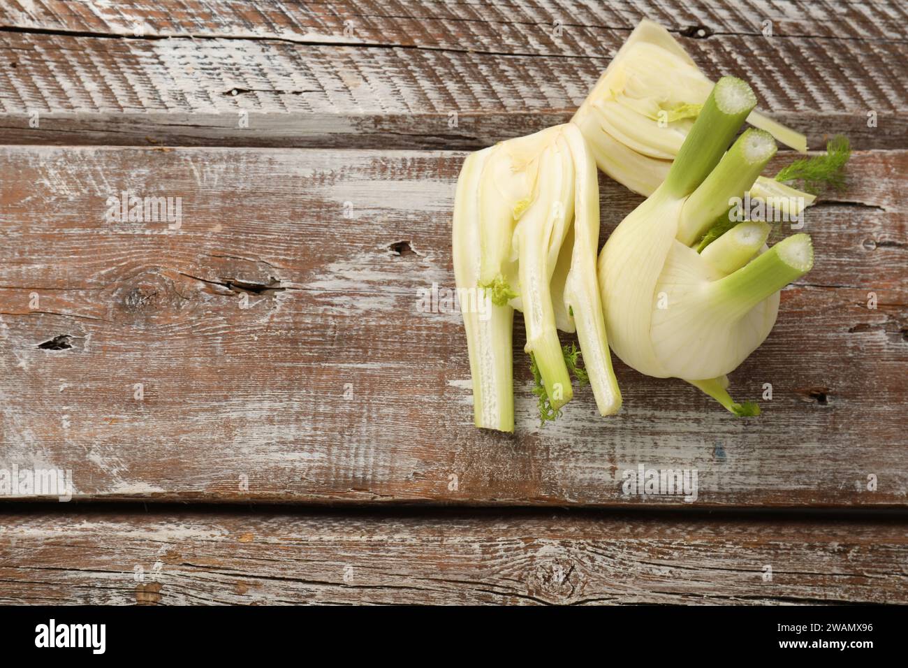 Whole and cut fennel bulbs on wooden table, top view. Space for text ...