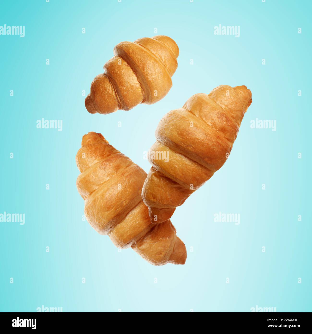 Golden croissants falling on cyan gradient background Stock Photo - Alamy