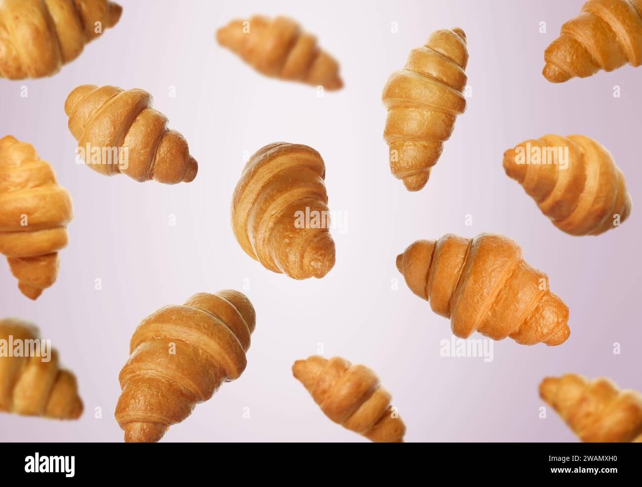 Golden croissants falling on pink gradient background Stock Photo - Alamy