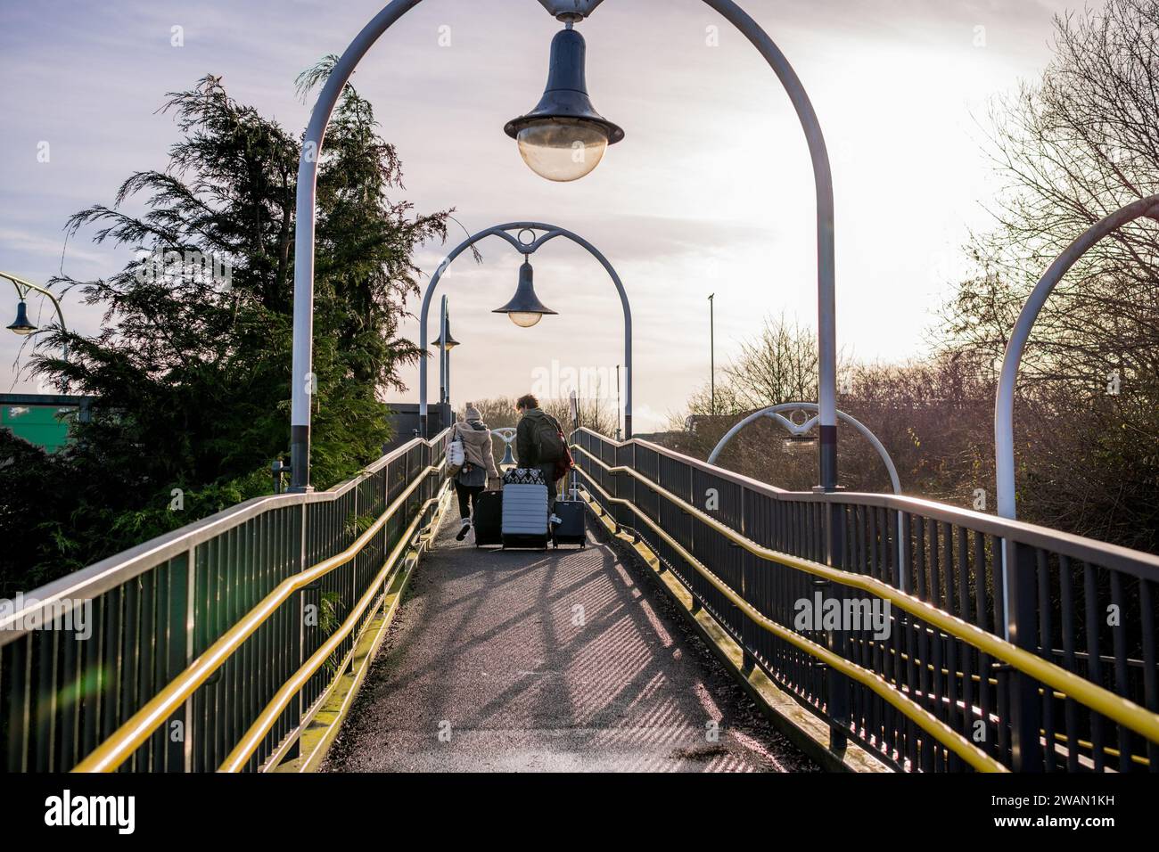Male and female train passengers wheel their cases up the walk way at ...