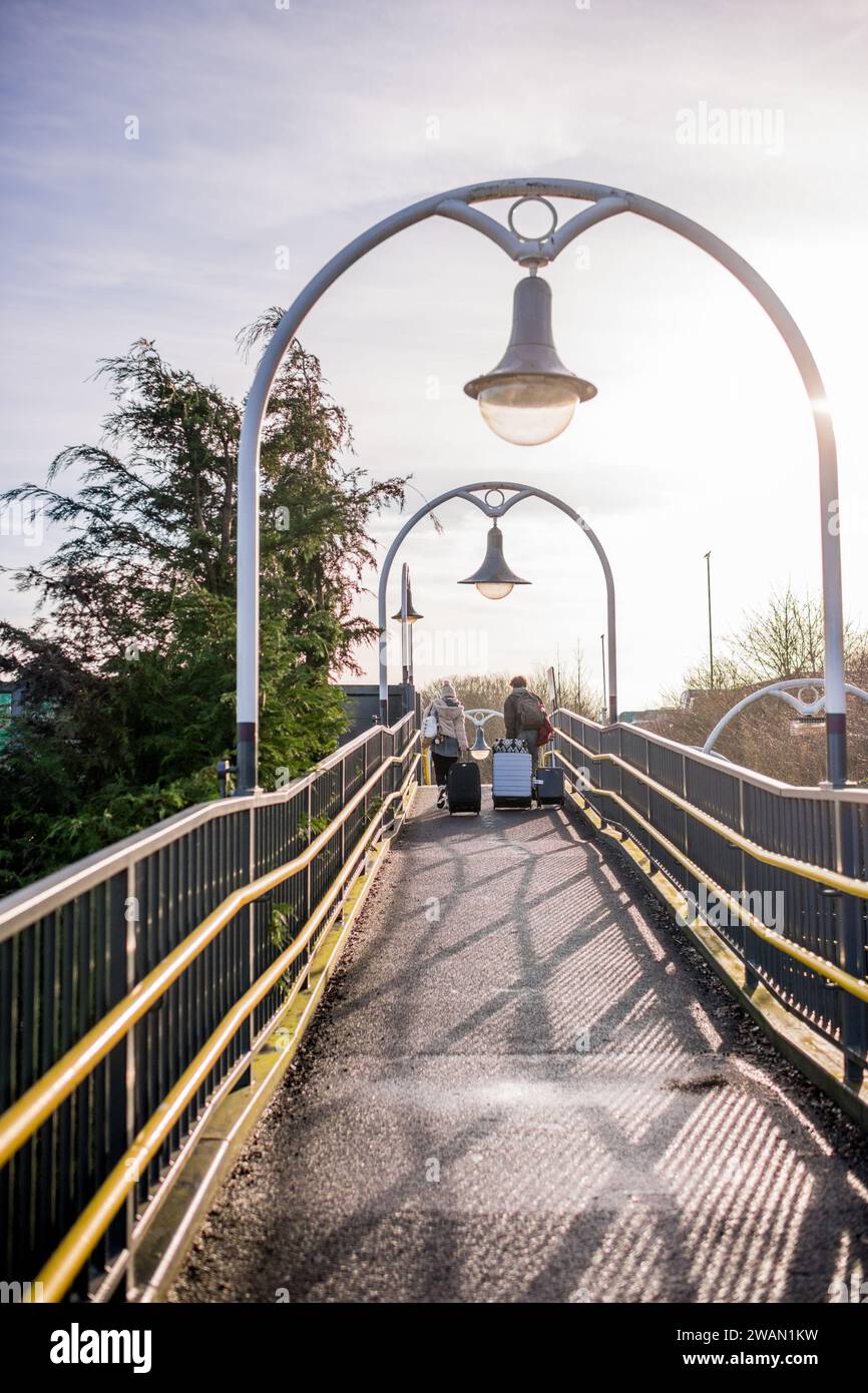 Male and female train passengers wheel their cases up the walk way at ...