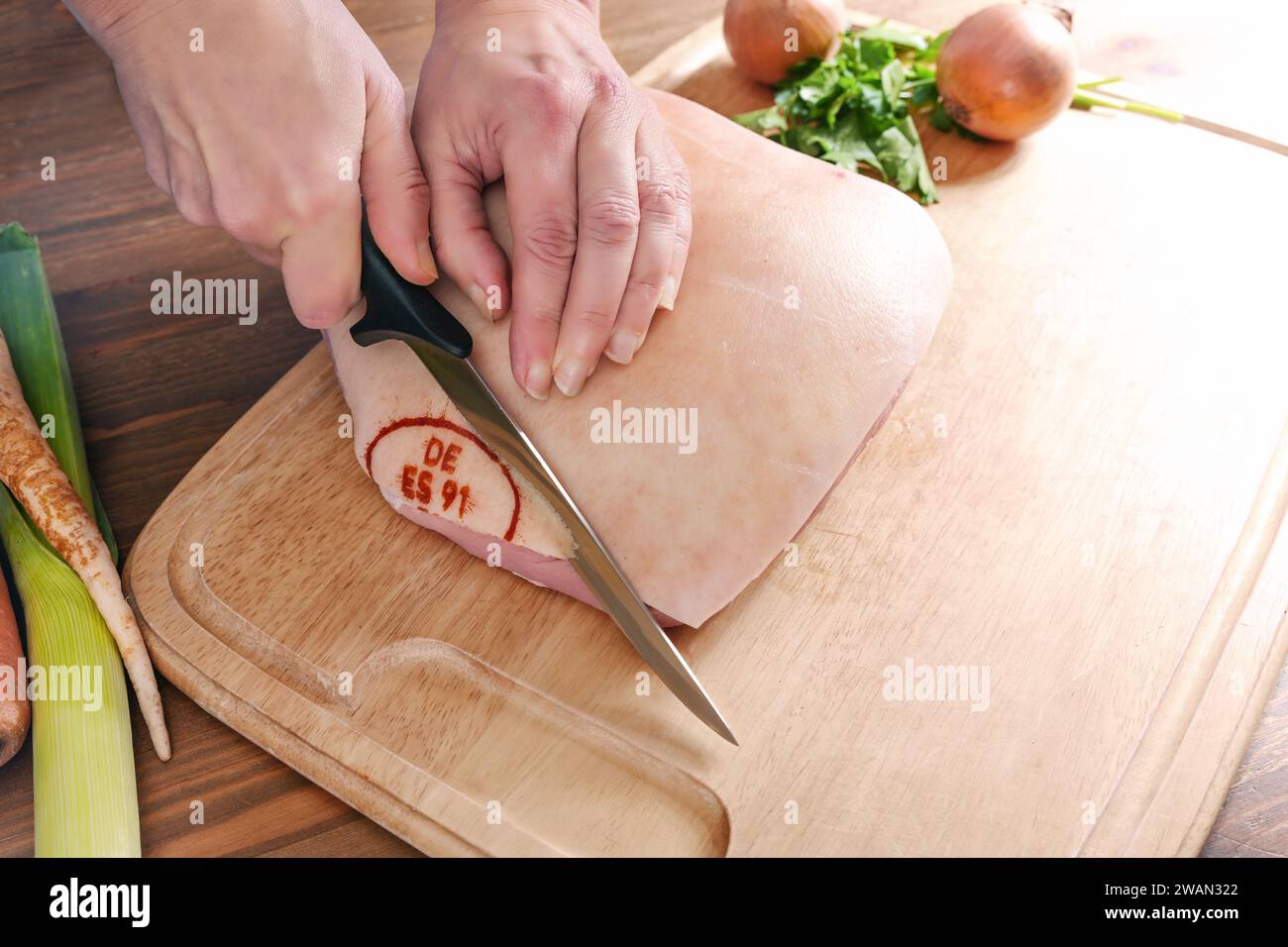 Hands of the cook with a sharp kitchen knife removing the control stamp ...