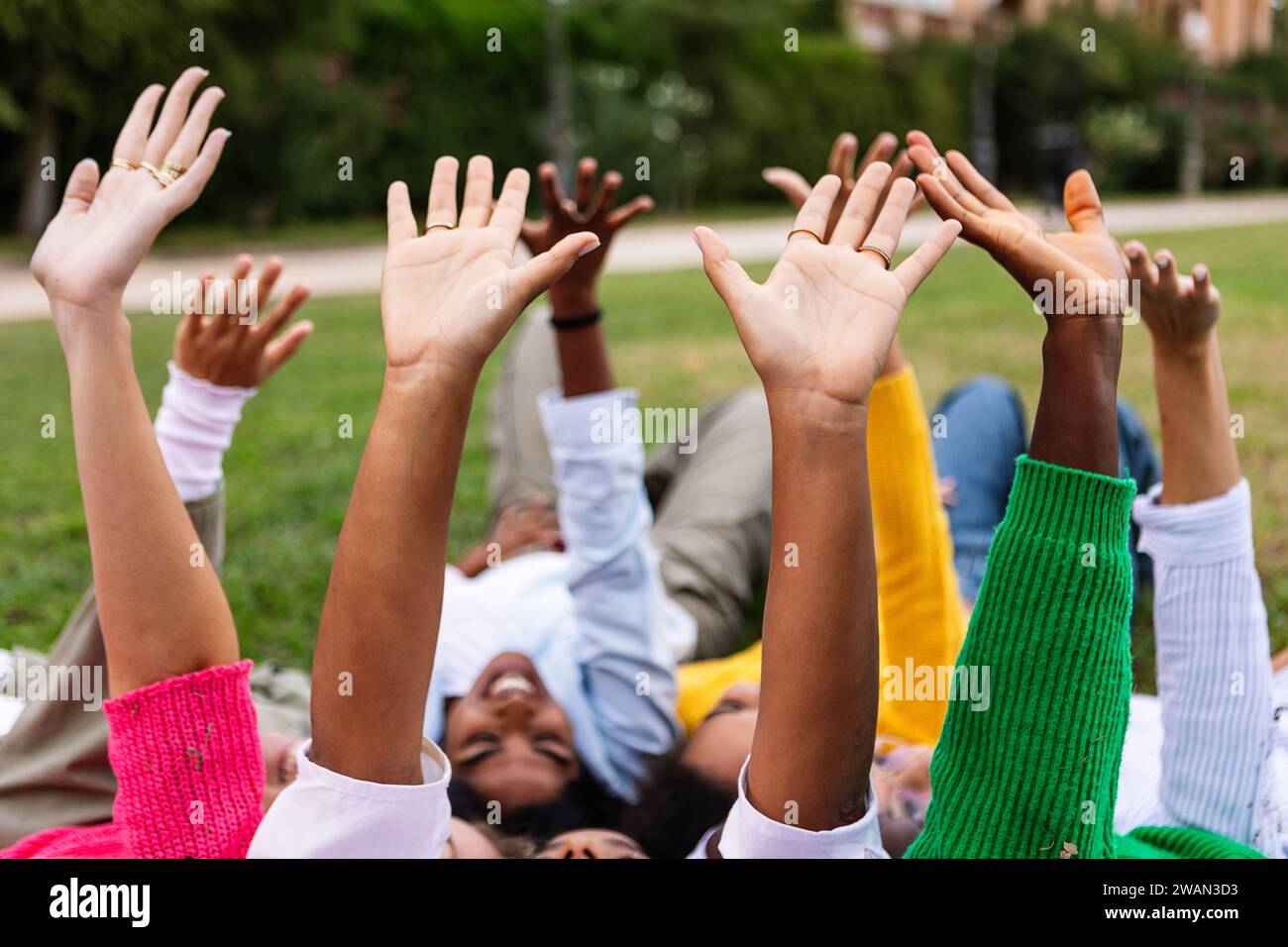 Group of diverse people with arms raised while lying together on city ...