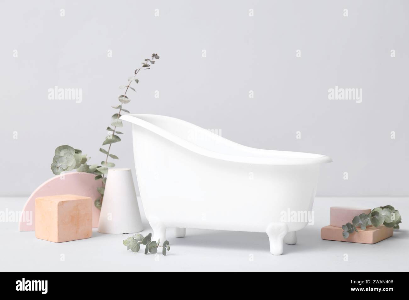 Small bathtub, plaster decor and eucalyptus branches on light ...