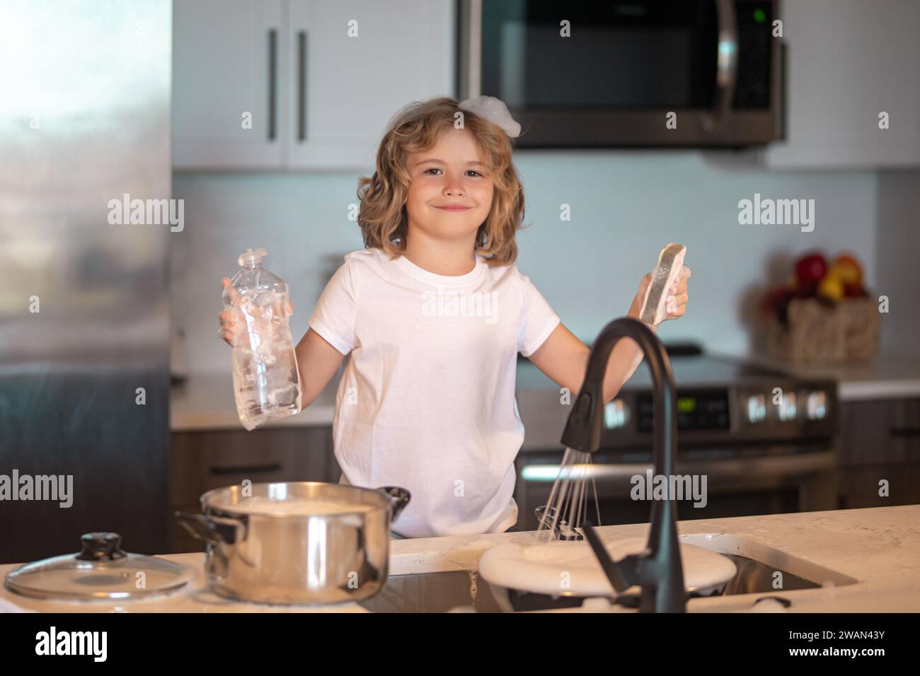 Funny twin boys helping in kitchen with washing dishes. Children having ...