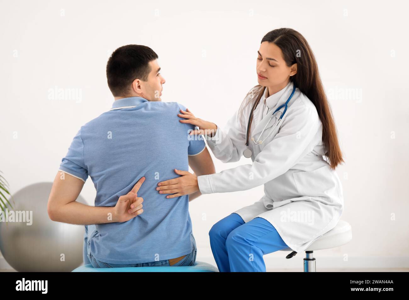 Female doctor checking posture of young man in clinic Stock Photo - Alamy