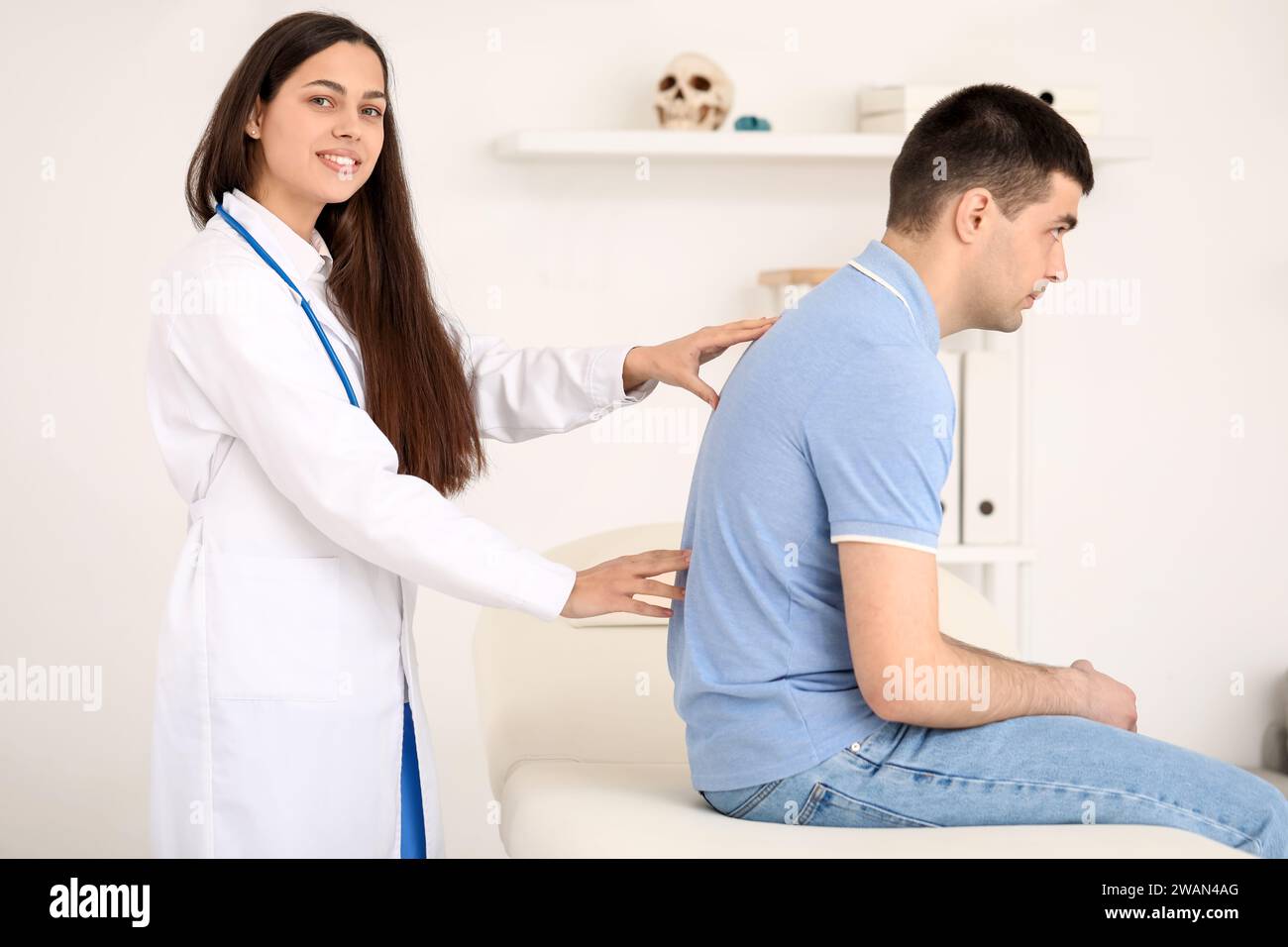 Female doctor checking posture of young man in clinic Stock Photo - Alamy