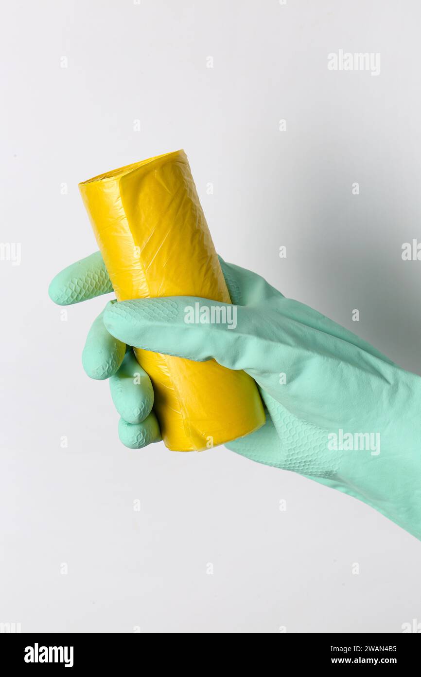 Hand in rubber glove with roll of garbage bags on white background ...