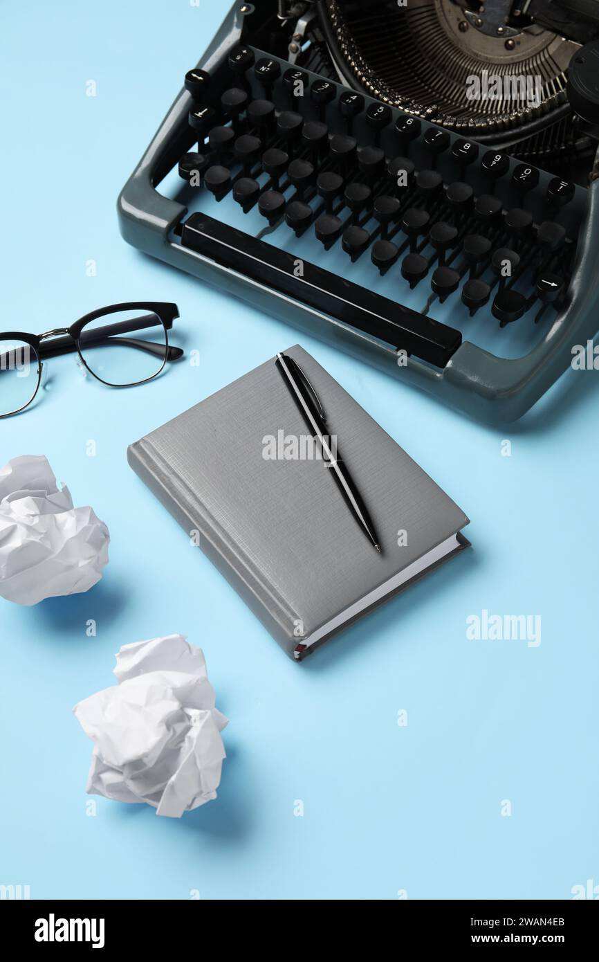 Vintage typewriter with crumpled paper, eyeglasses and notebook on blue ...