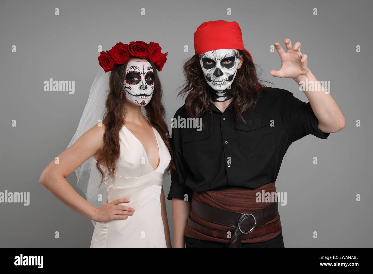 Couple in scary bride and pirate costumes on light grey background ...