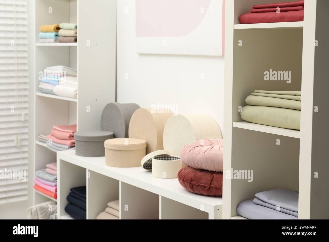 Different colorful bed linens and decorative boxes on display in home ...