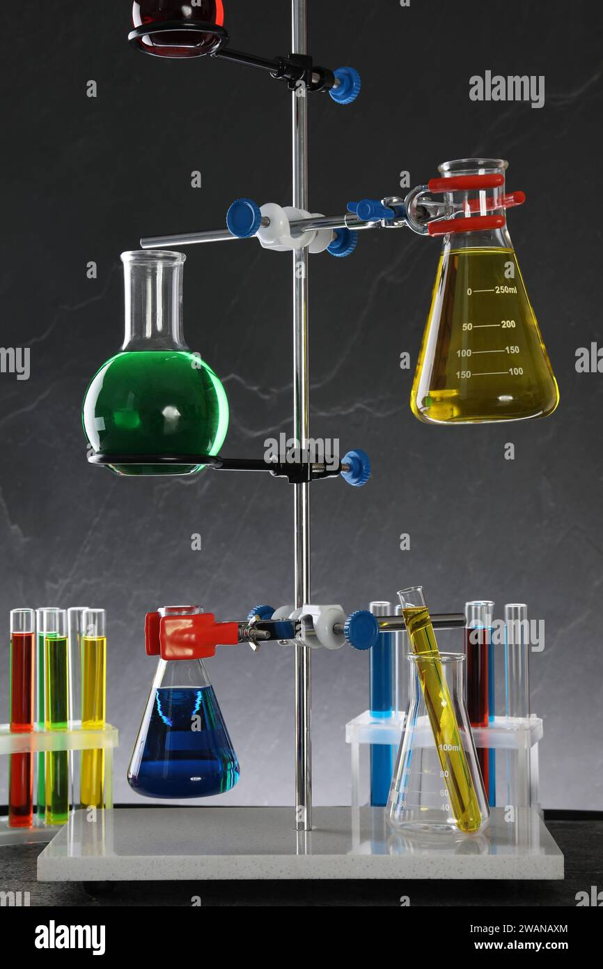 Retort stand and laboratory glassware with liquids on table against ...