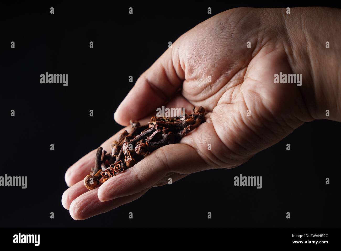 hand holding cloves in dark background Stock Photo - Alamy