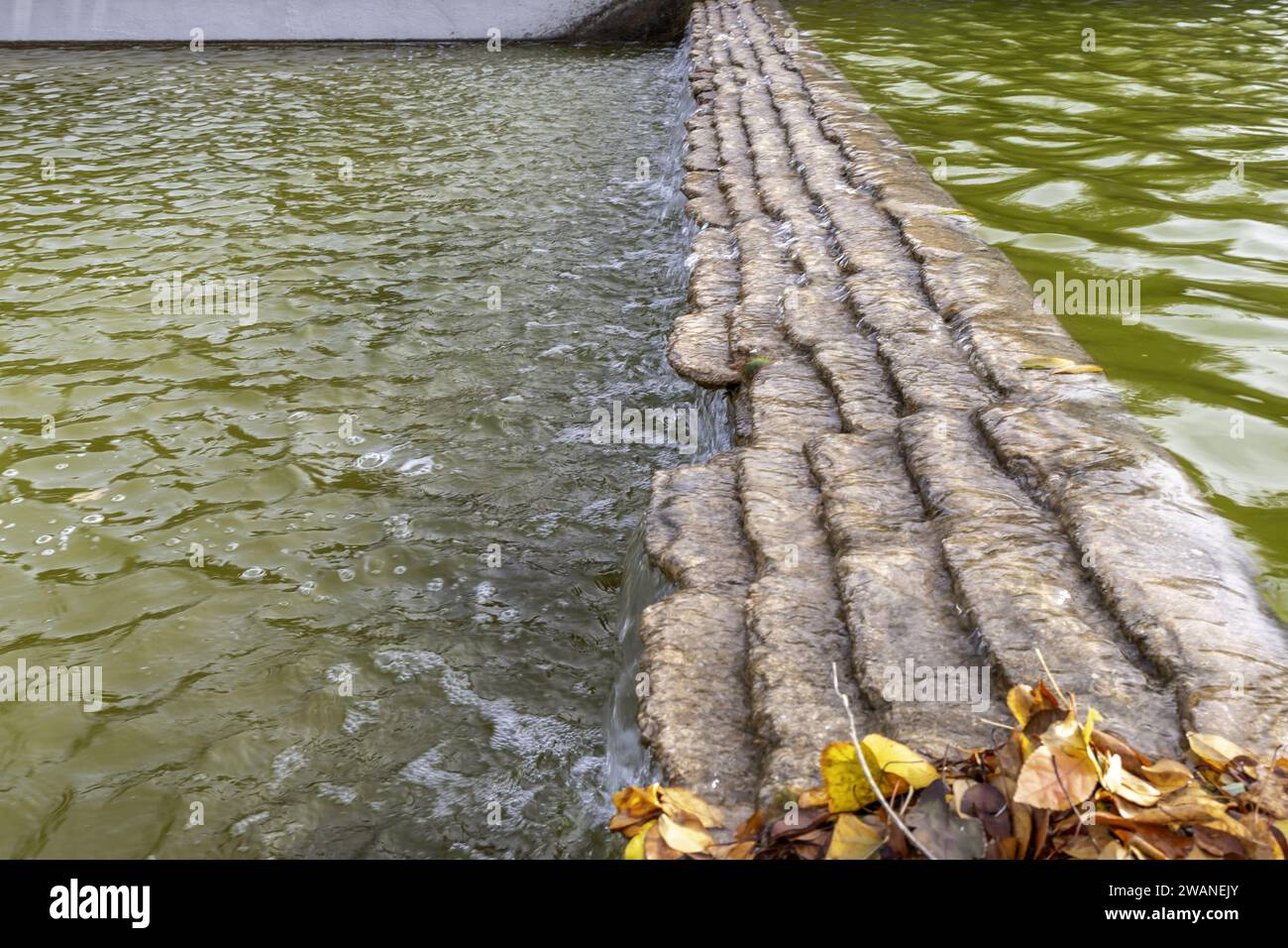 a water channel with a small artificial stone waterfall inside an urban ...