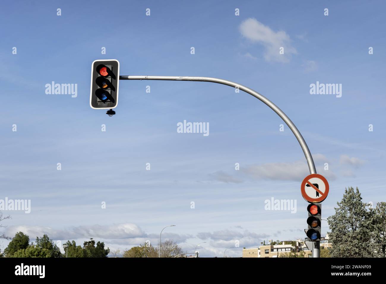 A curved pole holding a red traffic light and a no left turn sign Stock ...