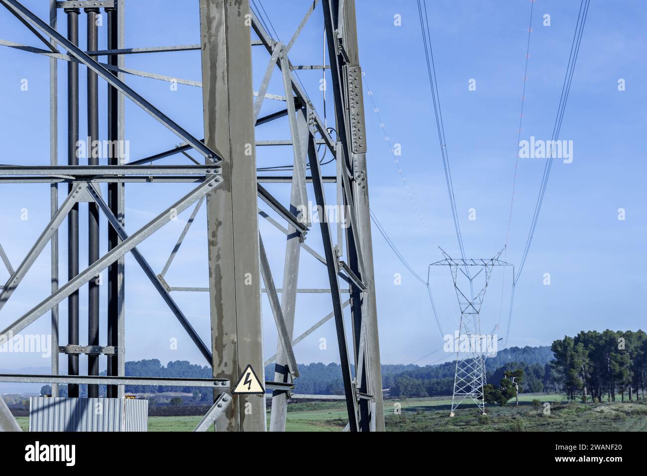 Metal towers carrying high voltage cables crossing a forested area ...