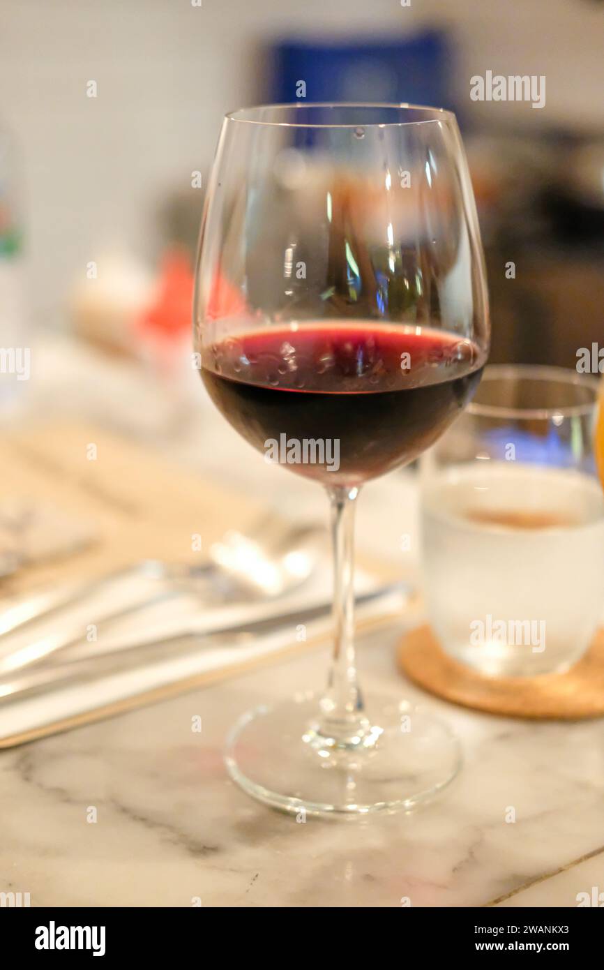 A glass of red wine on the table, with blur background in the ...