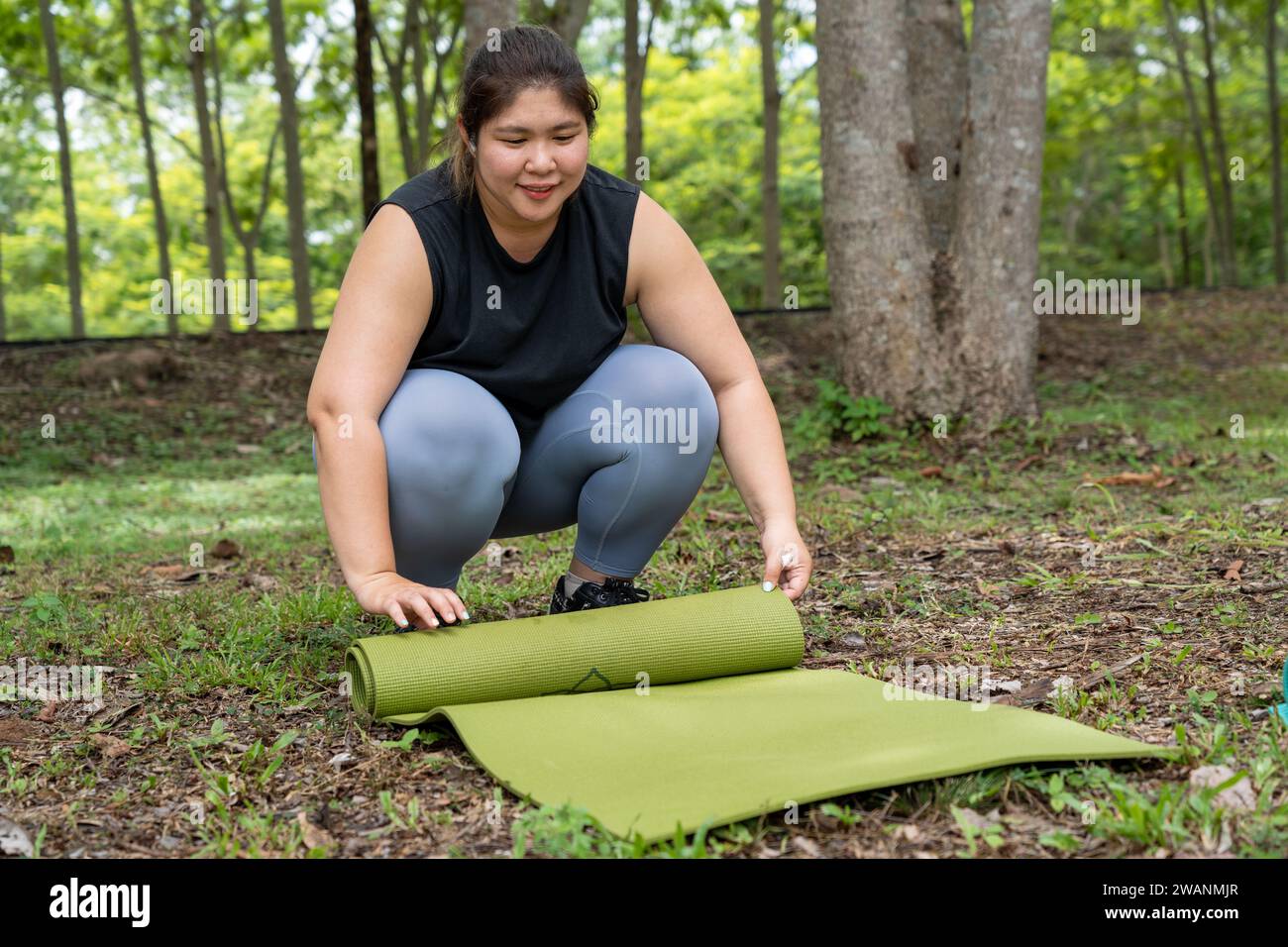 Asian plus size women in fitness clothes rolling up her yoga mat after ...