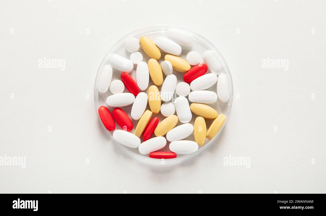 Various colorful pills in petri dish isolated on white, top view ...