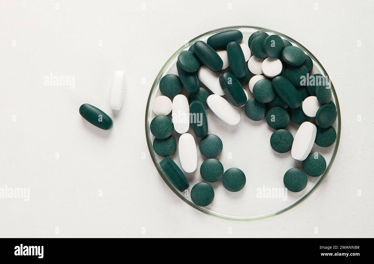 Various colorful pills in petri dish isolated on white, top view ...