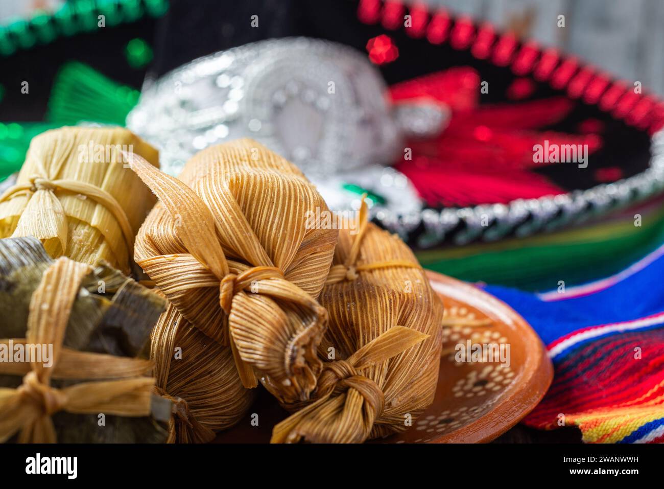 Different tamales in a clay dish on a colorful serape and mariachi hat ...