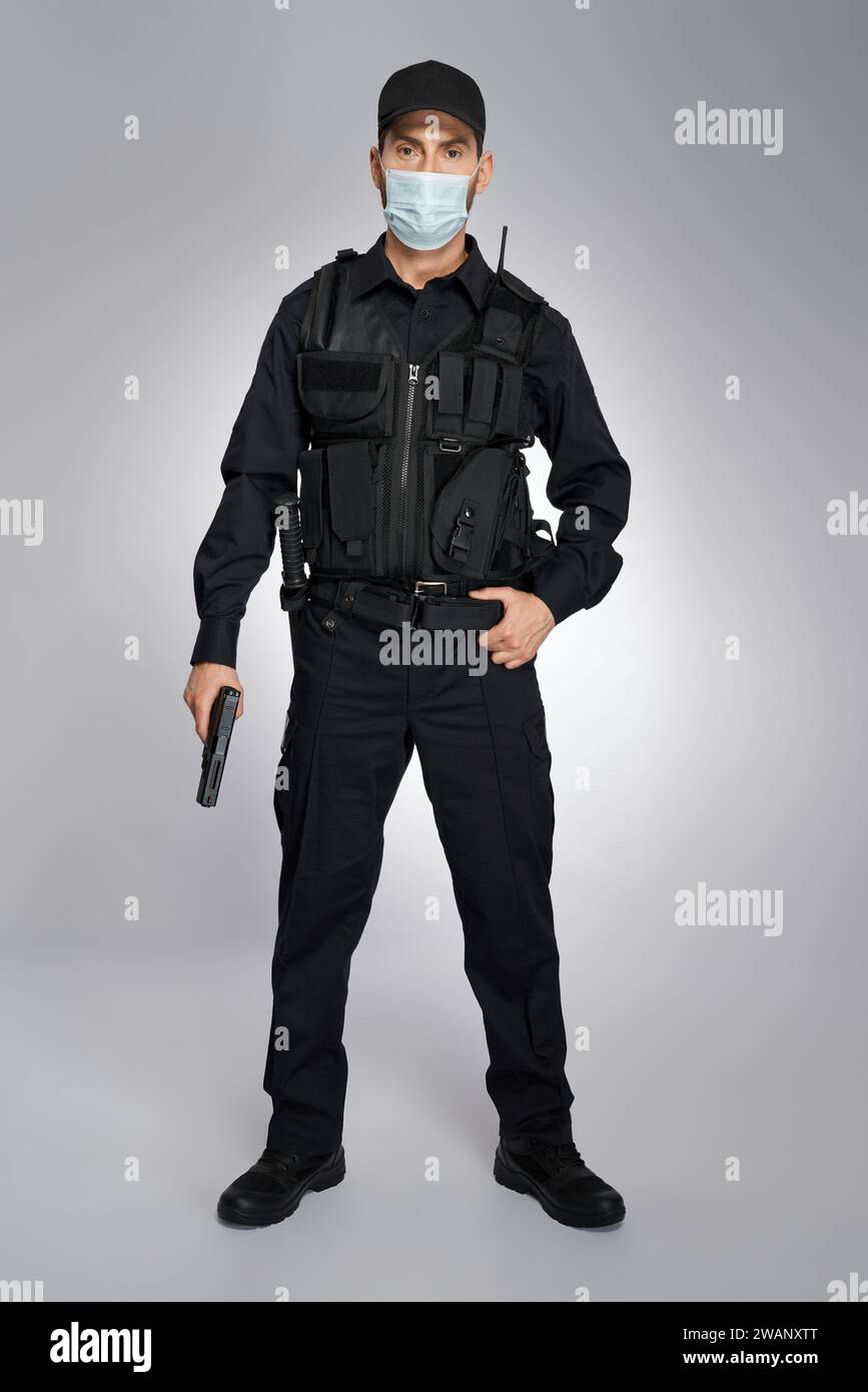 Tall male police officer wearing protective mask looking at camera in ...