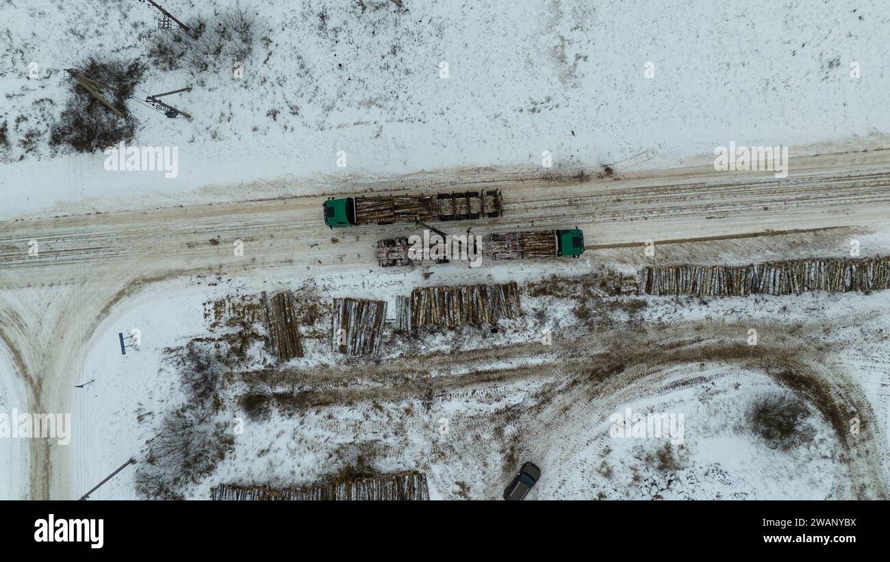 Drone photography of log lorry piking up logs during winter cloudy day ...