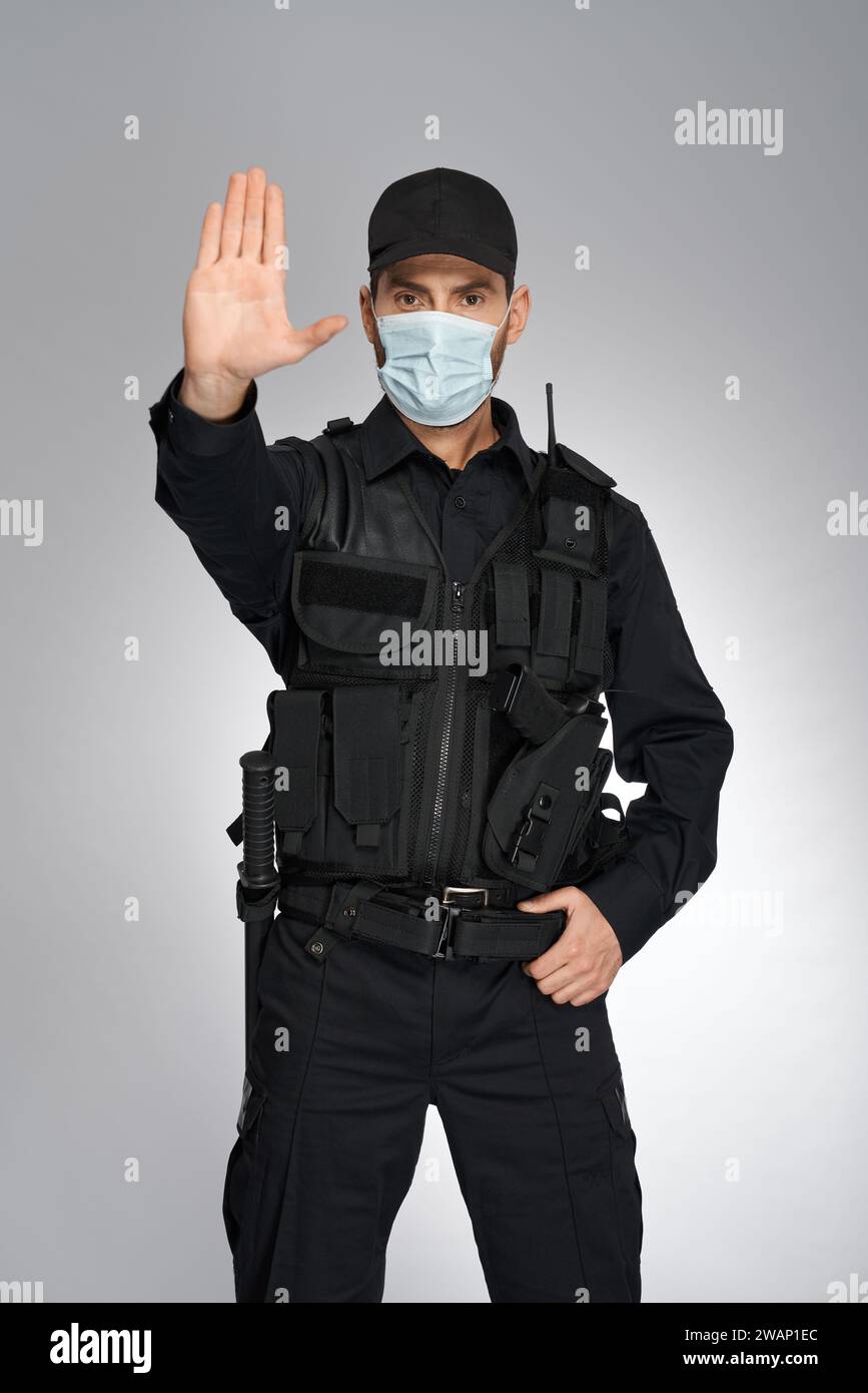 Serious police officer showing stop gesture with hand palm in studio ...