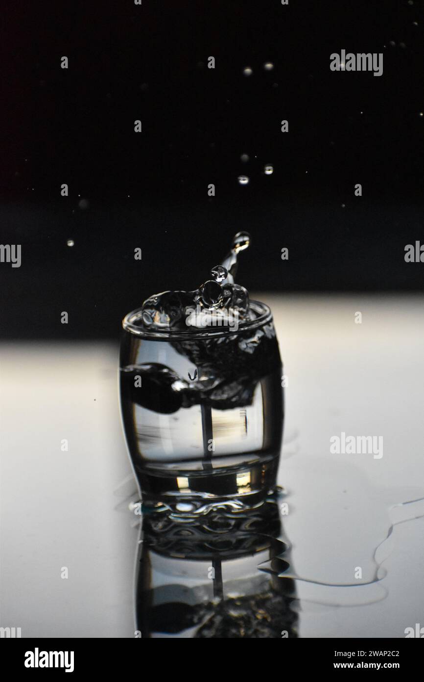 Water in motion: pebble strikes into a rim filled cup Stock Photo - Alamy
