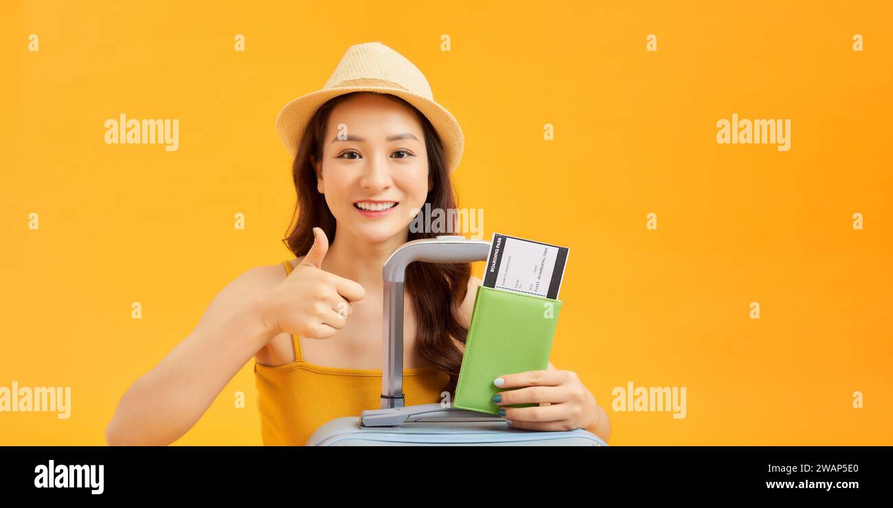 Dreamy asian tourist, smiling and thinking, holding tickets and ...