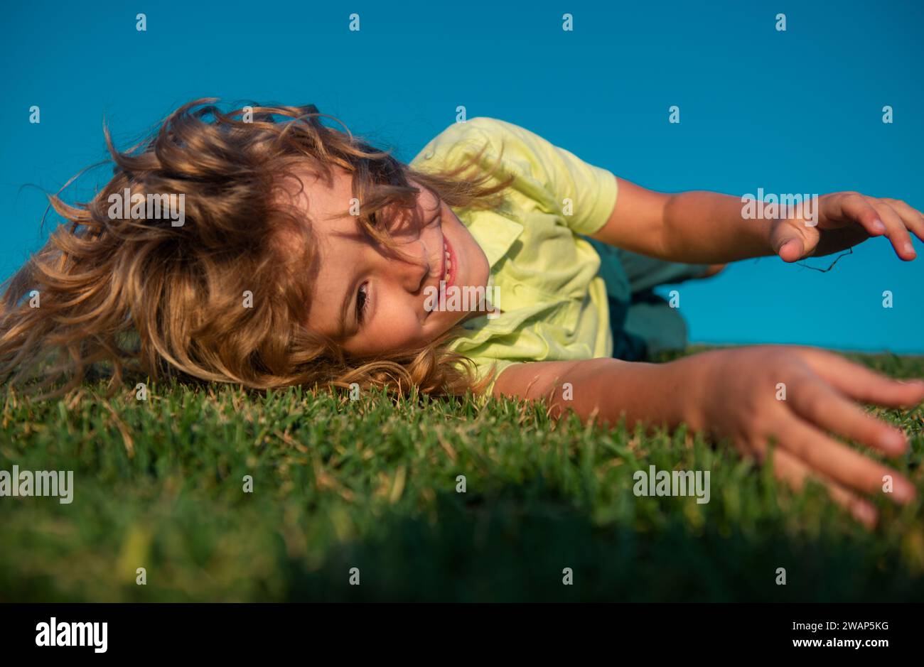 Portraits of happy kids playing and laying on grass outdoors in summer ...