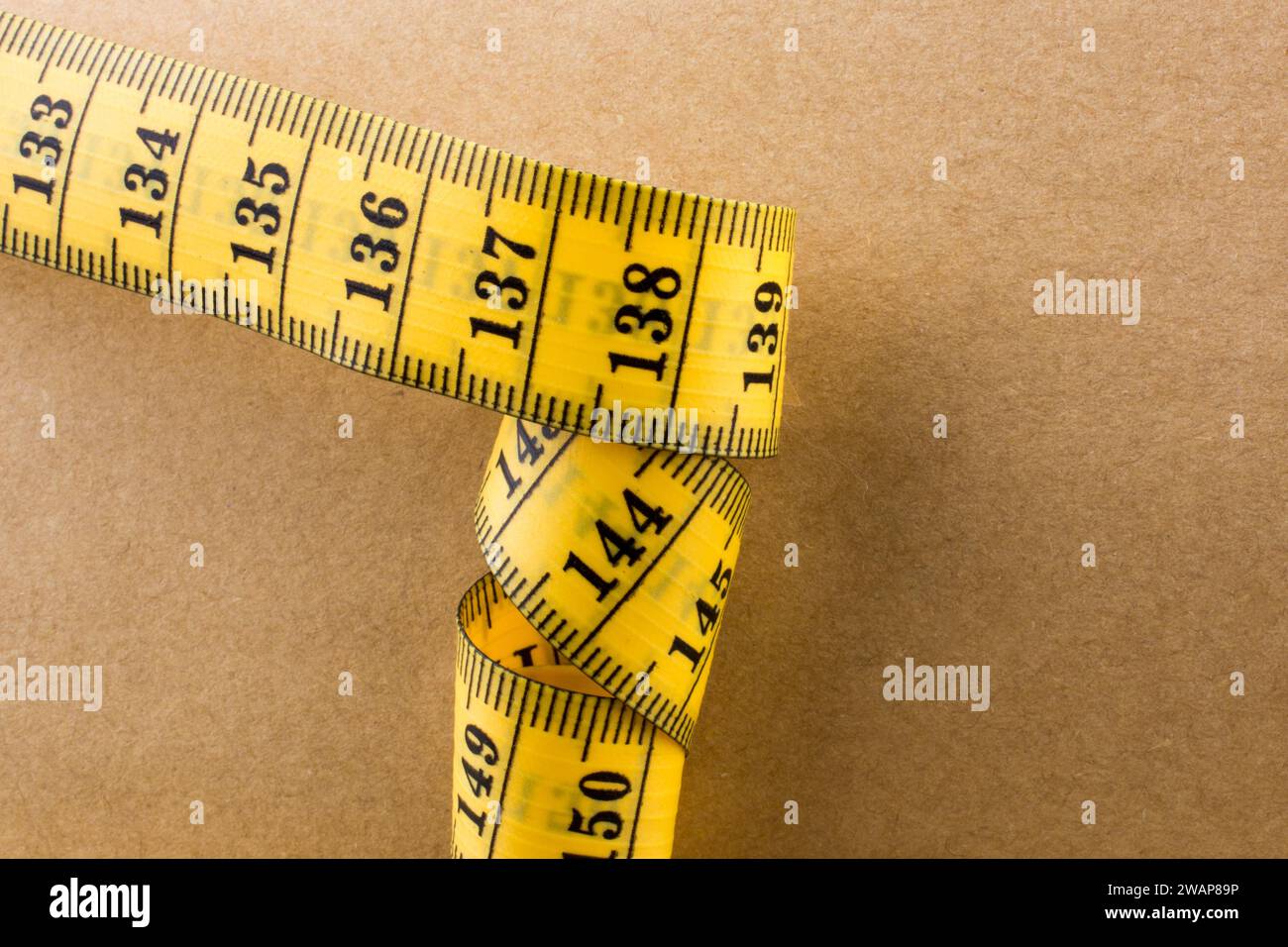 Yellow color Tape measure roll on a brown background Stock Photo - Alamy