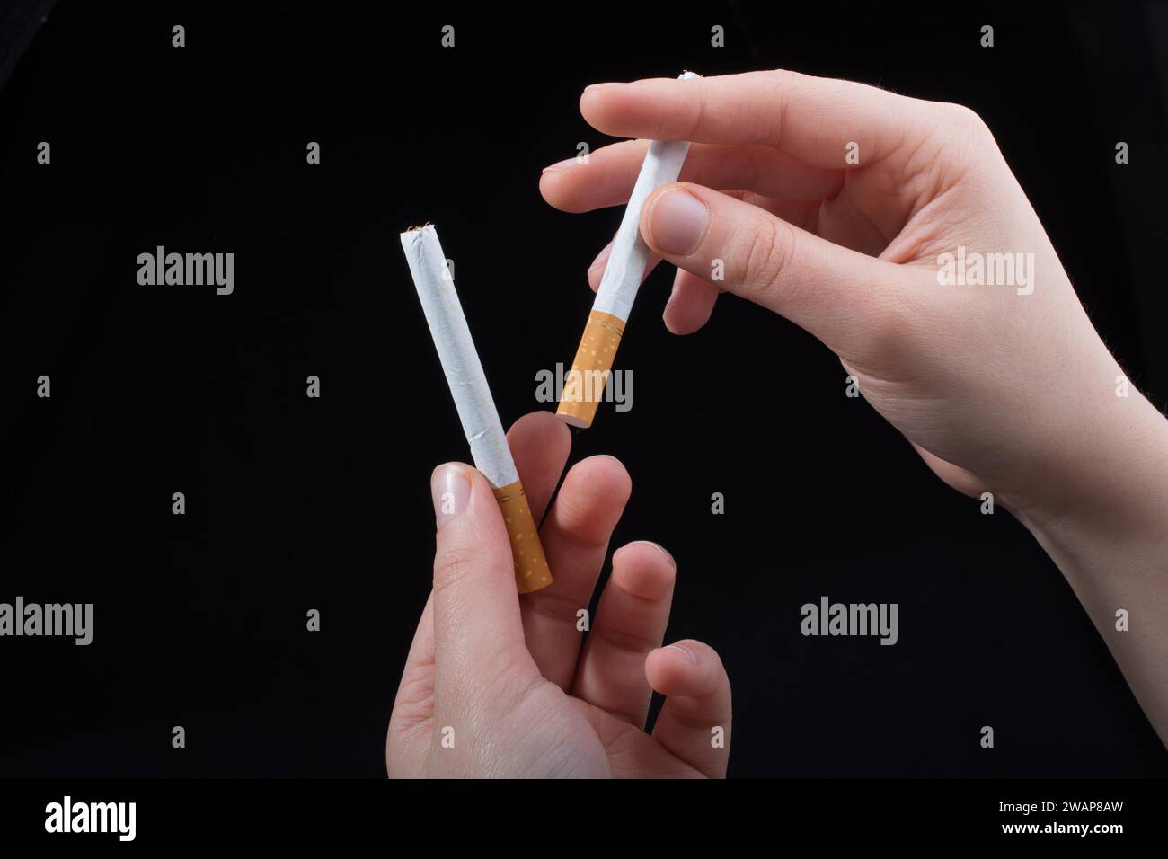 Hand is holding cigarettes on a black background Stock Photo - Alamy