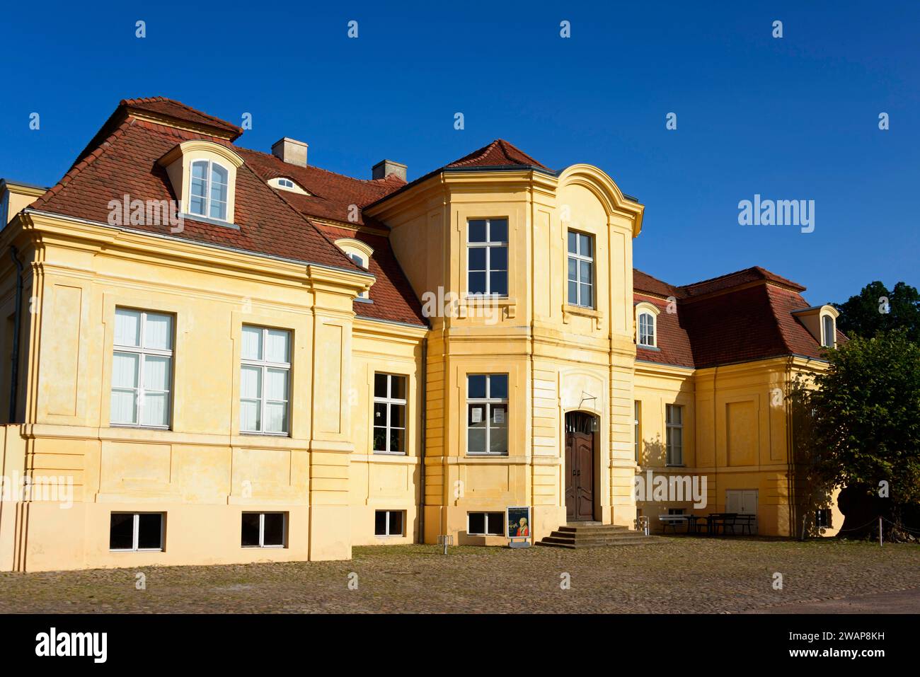 A sunlit baroque building painted yellow under a clear blue sky ...