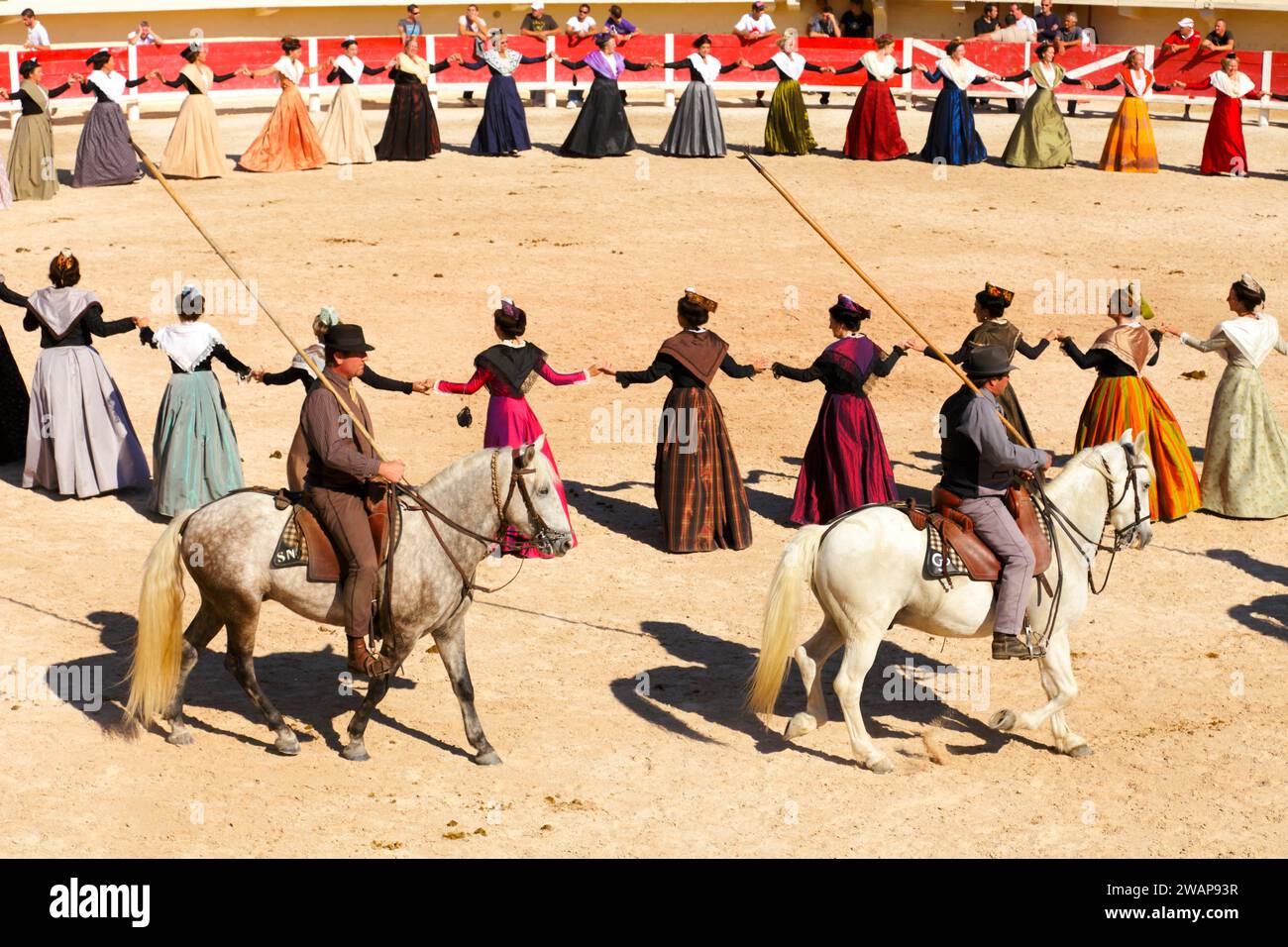 Women dance in traditional costumes and men ride horses in the arena of ...