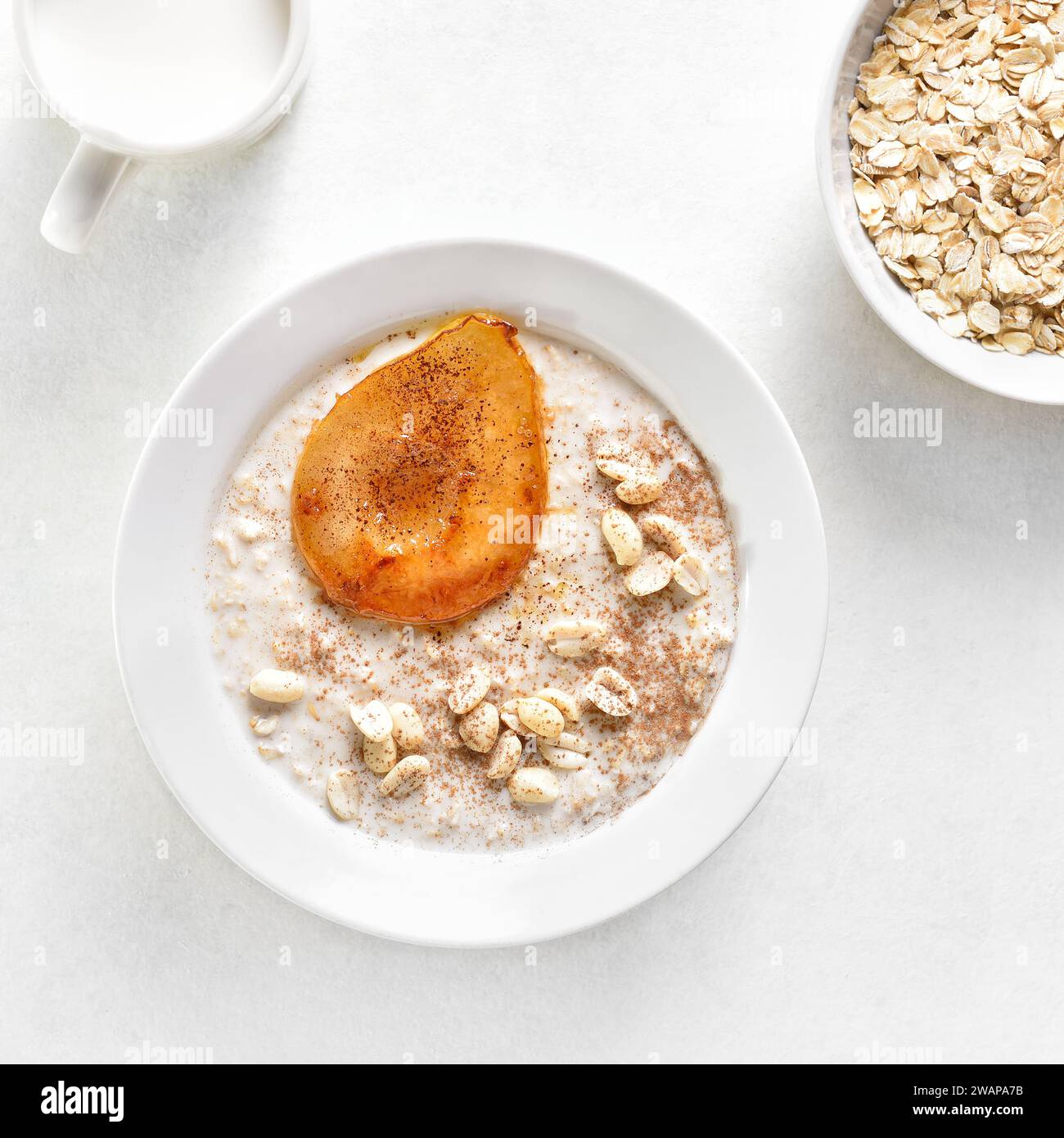 Oat porridge with caramelized pear and peanut in bowl over white ...