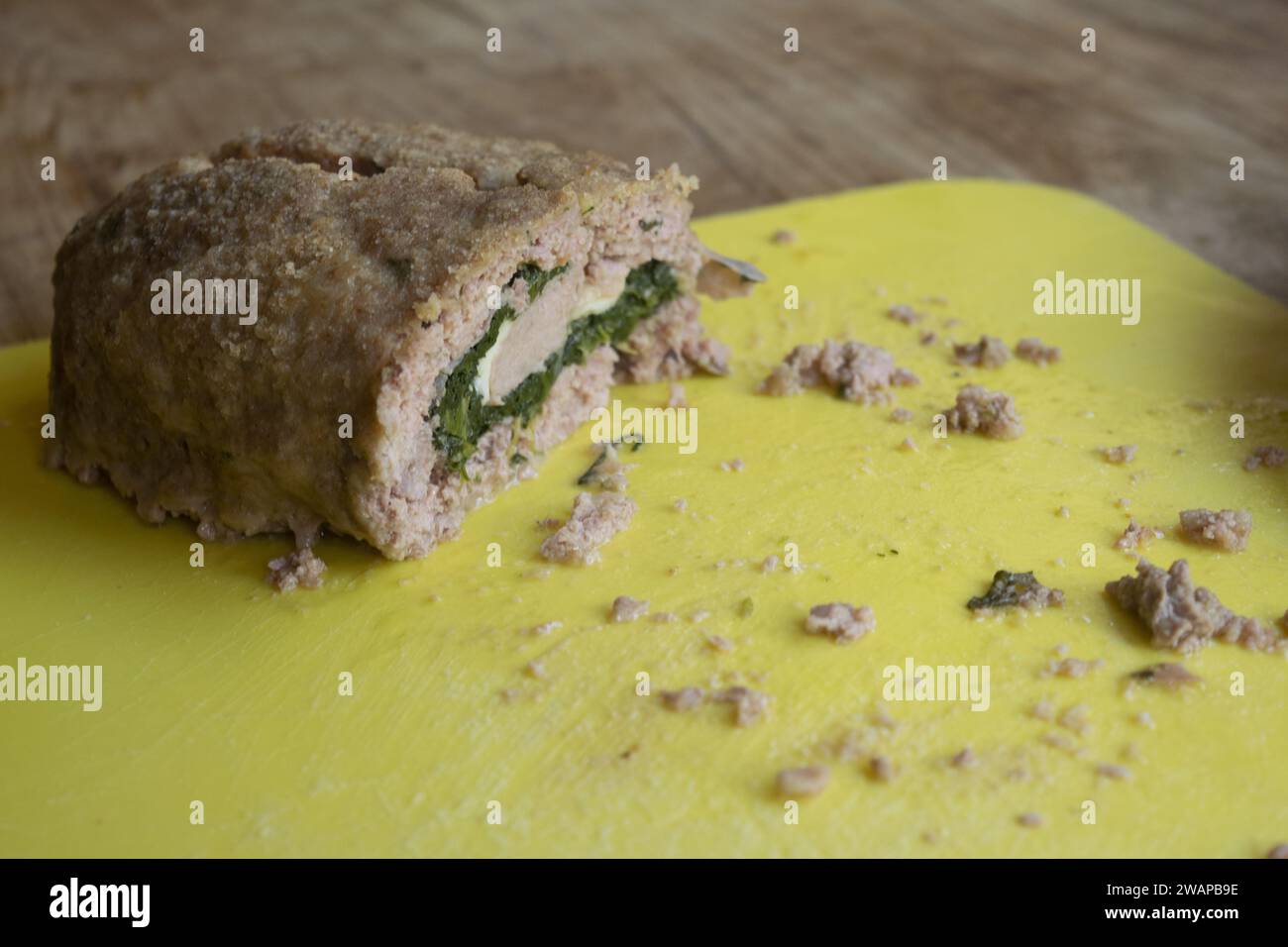 spinach meatloaf cut in half placed on a yellow cutting board Stock ...