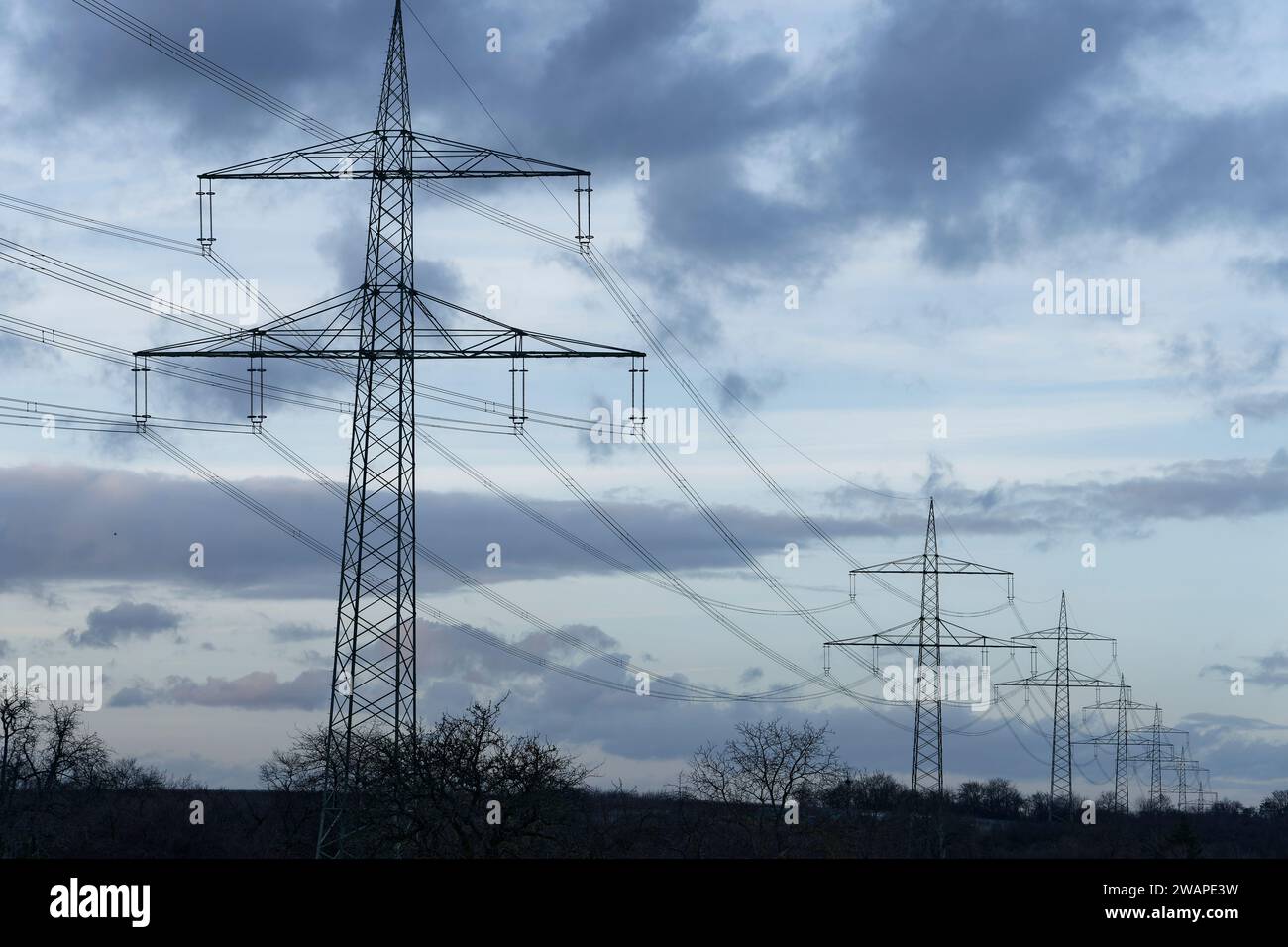 High-voltage pylons arranged in a row, extending to the rear with an ...