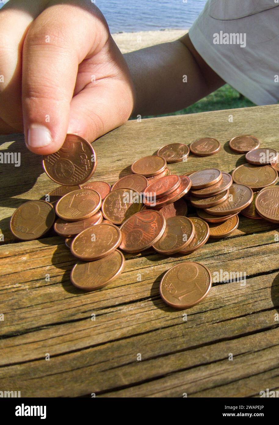 Little girl counting her pocket change savings. Weathered picnic table ...