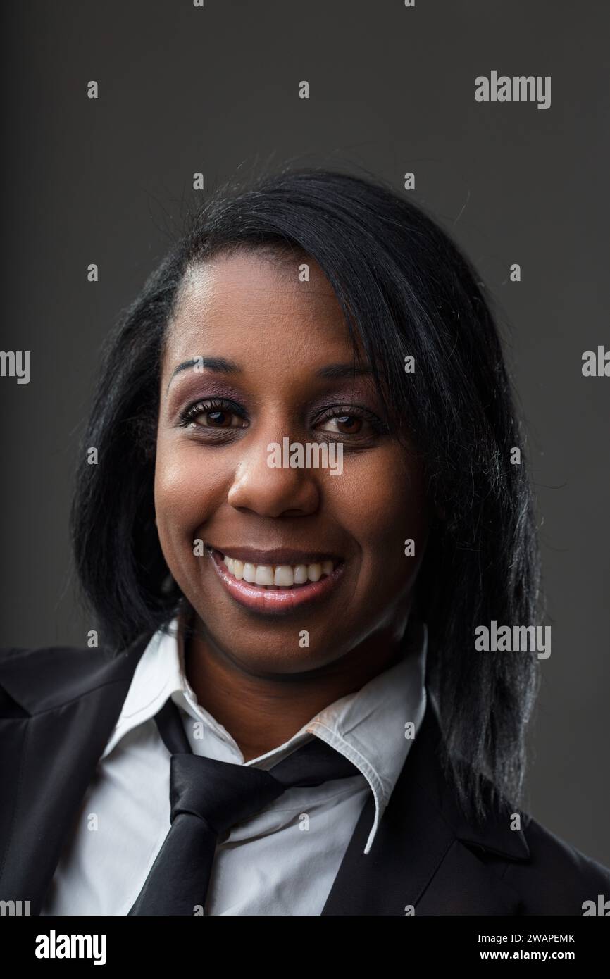 Black woman with a confident smile wearing a white shirt and black tie ...