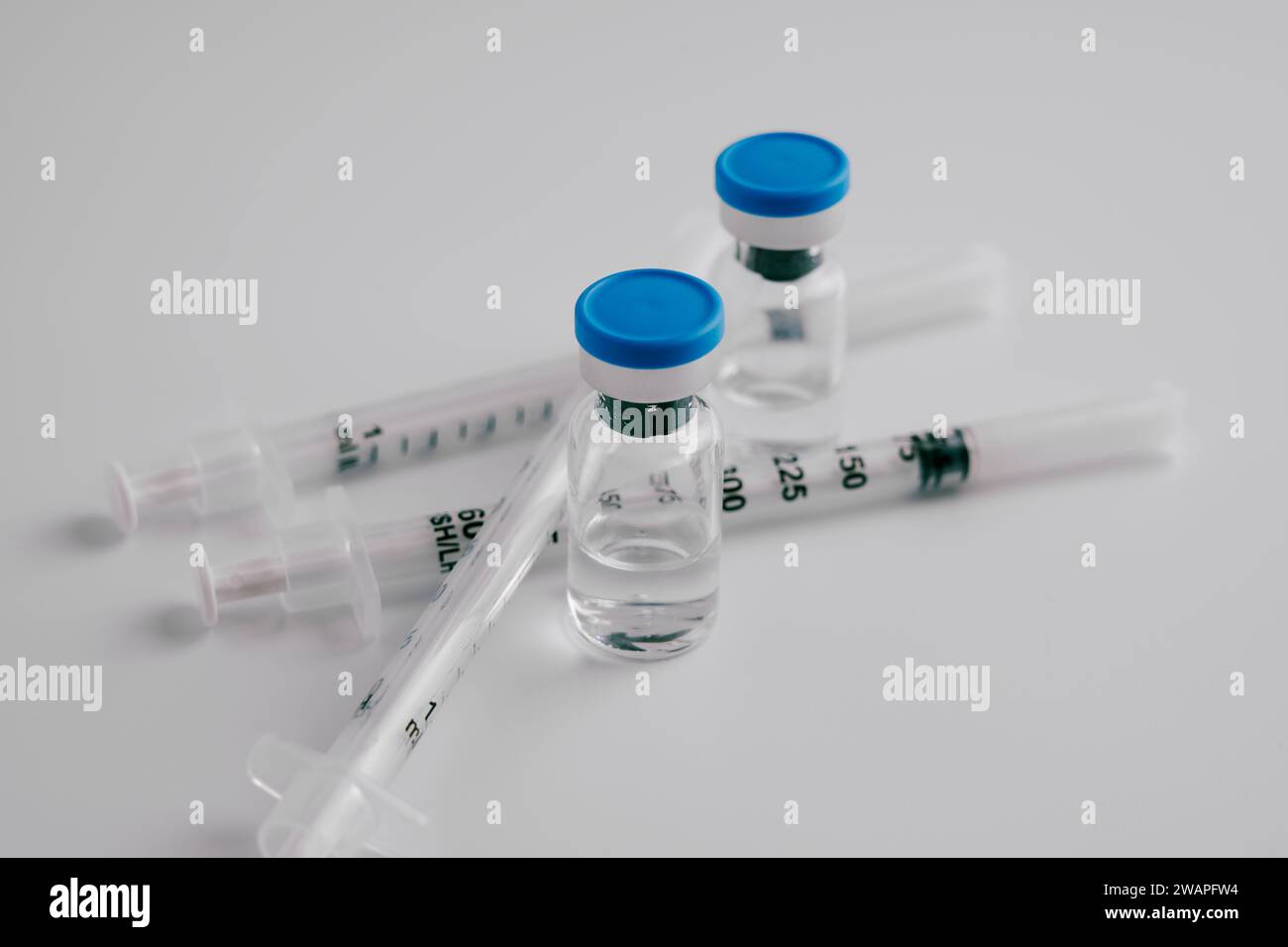 Two vials of vaccine with blue caps and syringes Stock Photo - Alamy